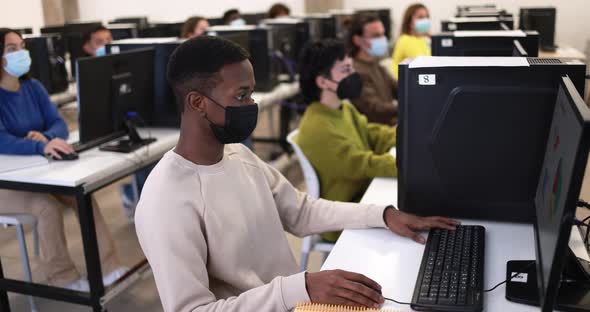 Young multiracial students using computers inside college class room ...