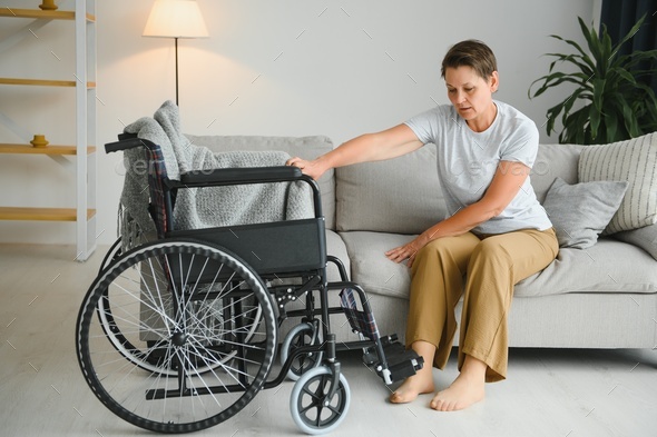Senior woman trying to sit down in wheelchair from couch Stock Photo by ...