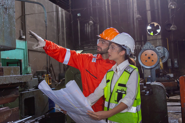 Two engineers in a steel mill Consult the size of the steel workpiece ...