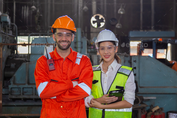 Two engineers in a steel mill Consult the size of the steel workpiece ...