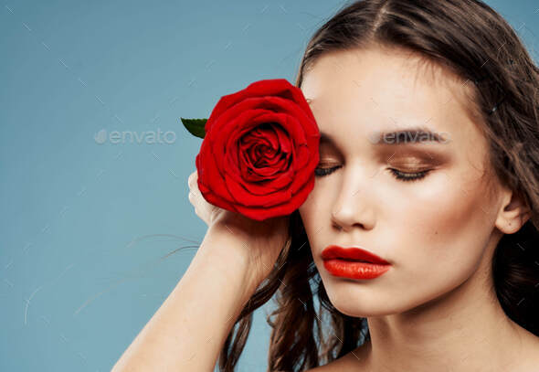 Young woman with red rose near face shadow on eyelids blue background model Stock Photo by shotprime