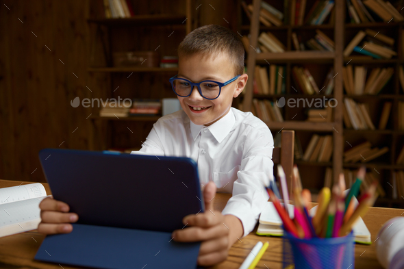 Cute smart boy schoolchild studying online using electronic device for ...