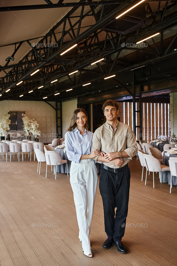 smiling couple in love looking at camera in modern banquet hall with ...