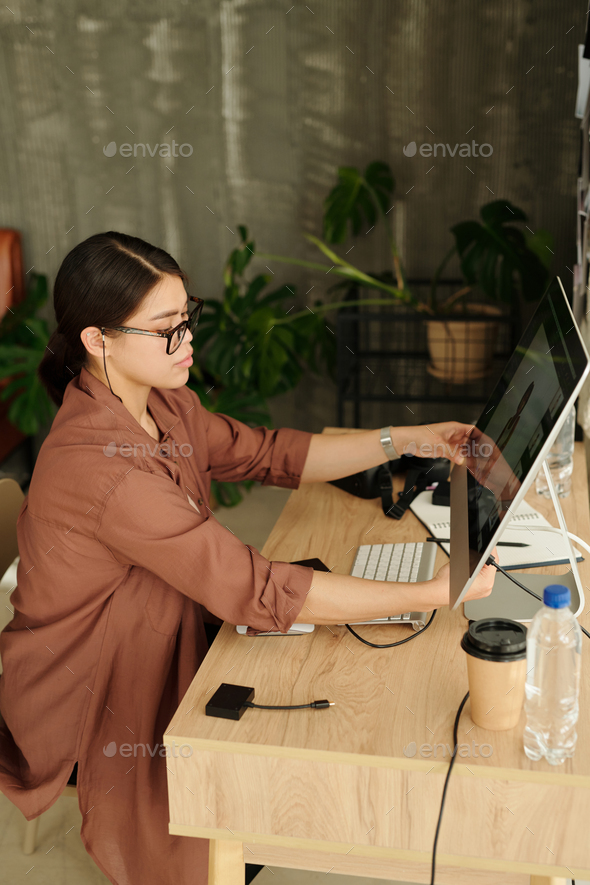 Side view of young female photographer adjusting computer monitor Stock ...