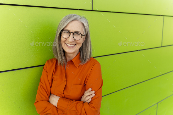Portrait Of Smiling Grey Haired Mature Woman Holding Arms Crossed