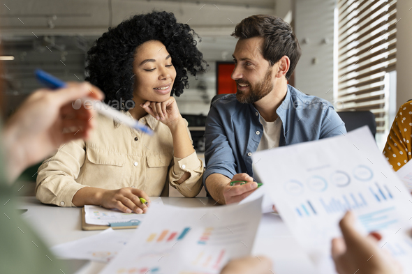 Two colleagues work together on new project with graphs and diagrams ...