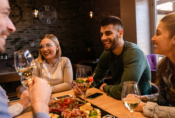 Group of young friends having fun in restaurant, talking and laughing ...