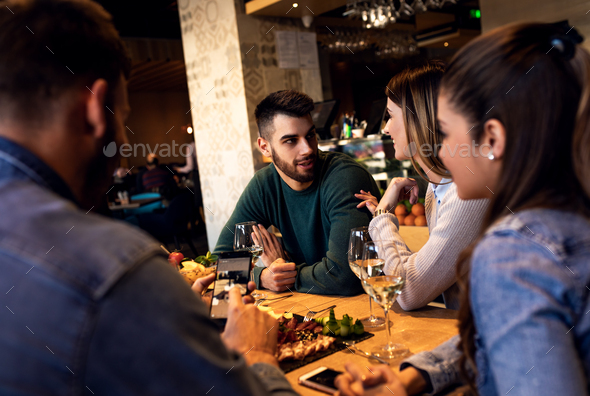 Group of young friends having fun in restaurant, talking and laughing ...