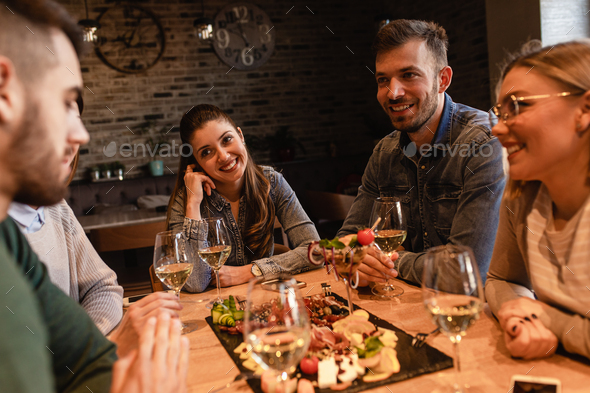 Group of young friends having fun in restaurant, talking and laughing ...
