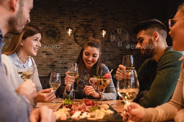 Group of young friends having fun in restaurant, talking and laughing ...