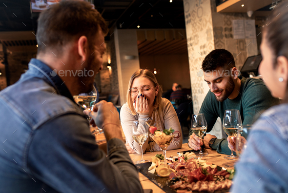 Group of young friends having fun in restaurant, talking and laughing ...
