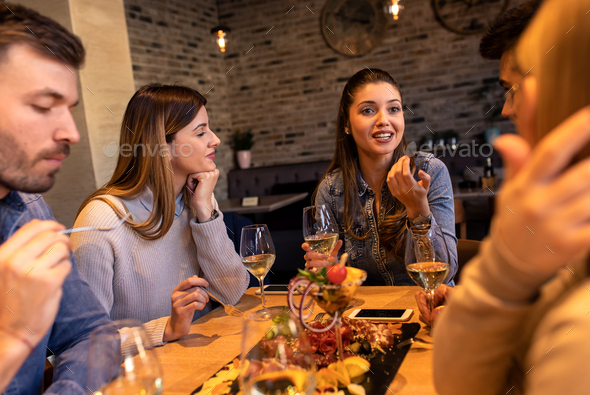 Group of young friends having fun in restaurant, talking and laughing ...