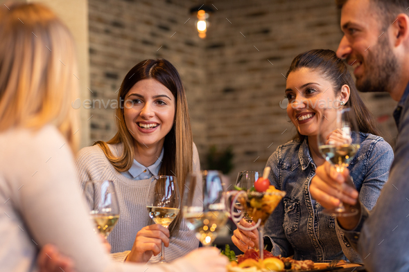 Group of young friends having fun in restaurant, talking and laughing ...