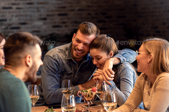 Group of young friends having fun in restaurant, talking and laughing ...
