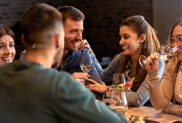 Group of young friends having fun in restaurant, talking and laughing ...