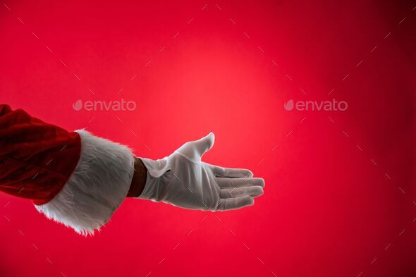 Santa Claus hand reaching out with an open palm on a red background ...