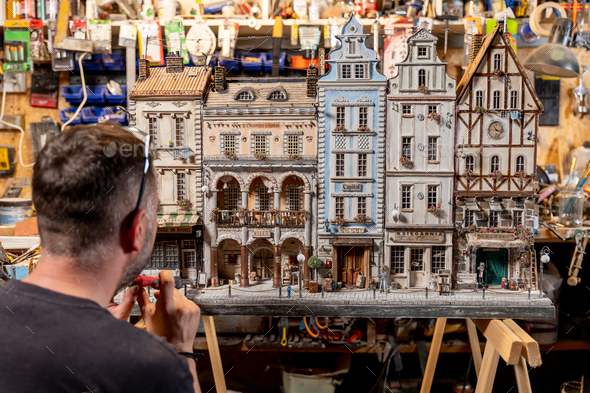 Modeller man working at scale model of miniature building in his ...