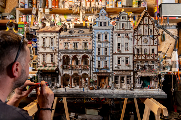 Modeller man working at scale model of miniature building in his ...