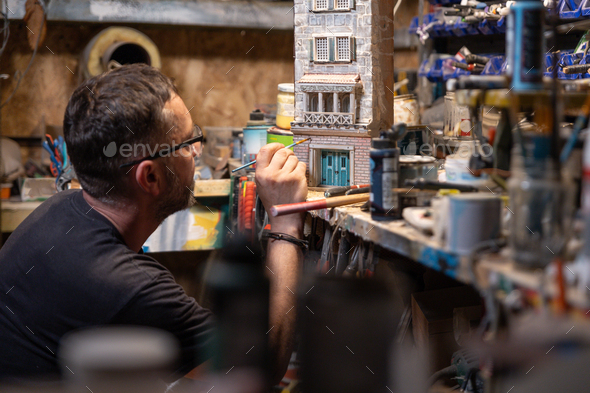 Modeller man working at scale model of miniature building in his ...