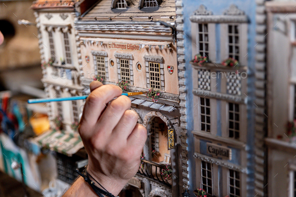 Modeller man working at scale model of miniature building in his ...