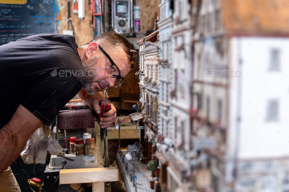 Modeller man working at scale model of miniature building in his ...