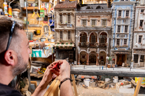 Modeller man working at scale model of miniature building in his ...