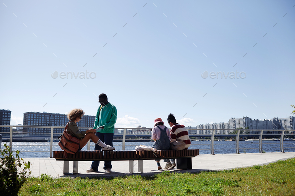 Back view at diverse group of young people relaxing outdoors gainst ...