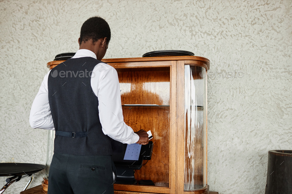 Back view of waiter using computer system in restaurant and putting ...