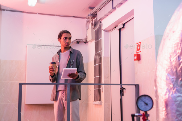 afican american programmer with digital tablet and coffee to go working ...