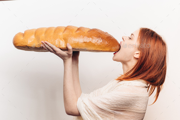 hungry woman eating large loaf of bread loaf side view light background ...
