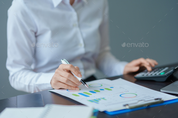 Close-up of a business woman analyzing charts and graphs for comparison ...