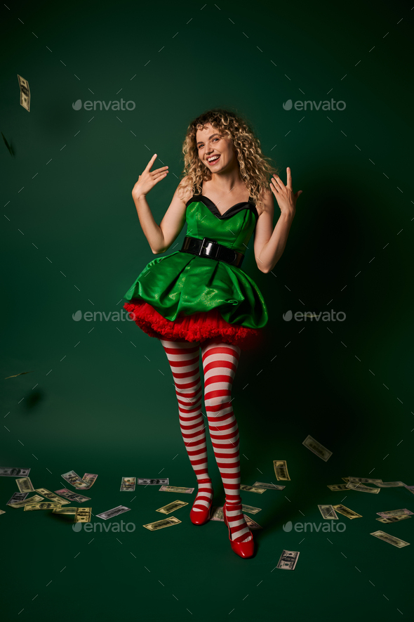 smiley new year elf in green dress and stockings gesturing and smiling ...
