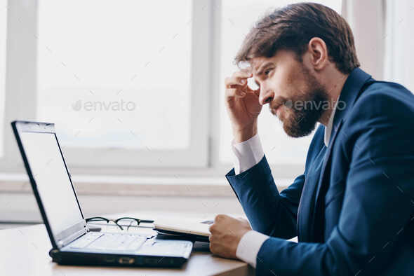 manager in the office at the desk in front of a laptop career ...