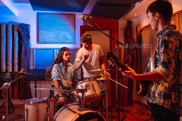 Musicians, drummer and guitarist, talking with their producers in music ...