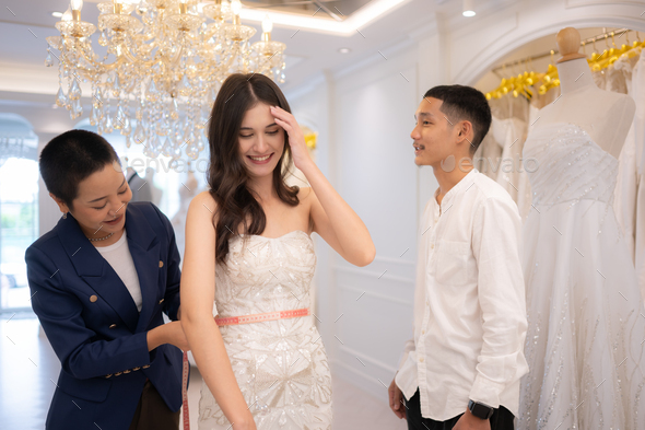 Bridal gown designers and tailors measure the size of the gown against ...