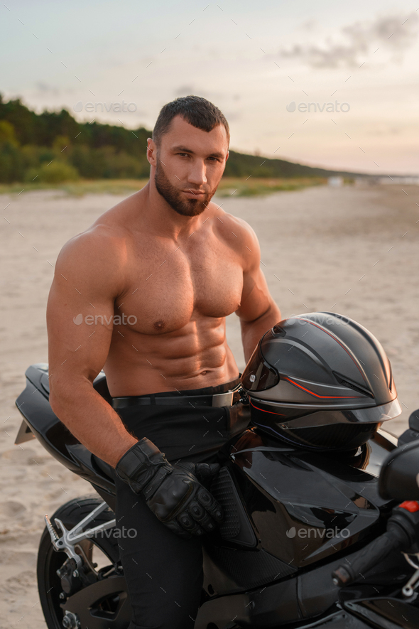 Ripped man with muscular torso on his black sports motorcycle on ...