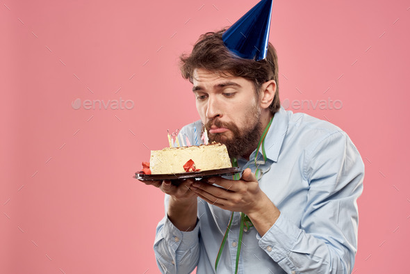 Man with cake in a plate and in a blue shirt on a pink background ...