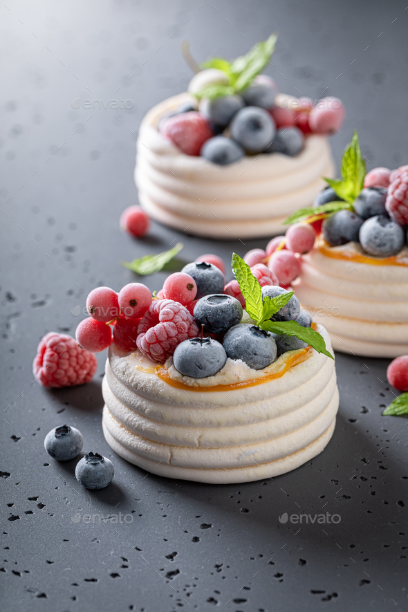 Creamy mini Pavlova dessert with frozen fruit and whipped cream. Stock ...