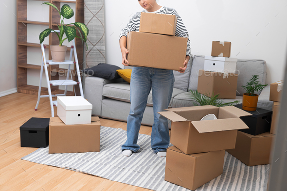 woman carries stack of cardboard relocation boxes into her new living ...