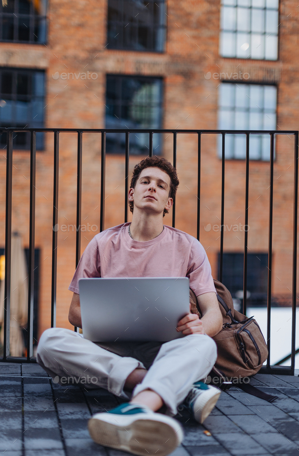 Gen Z student working on laptop after lecture on campus. Young stylish ...