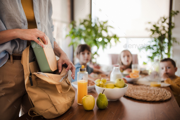 Mother packing school snacks for her children into school bag. Snack ...