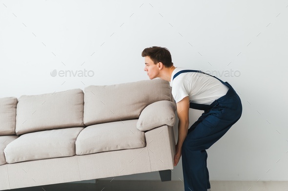 Loader moves sofa, couch. worker in overalls lifts up sofa, white ...