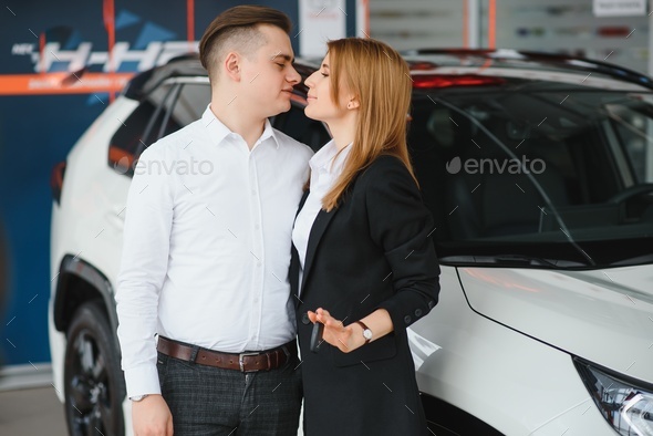 Visiting car dealership. Beautiful couple is holding a key of their new ...