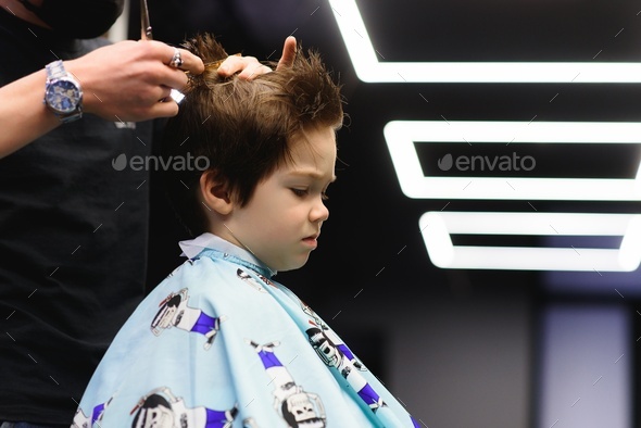 Cheerful Caucasian boy getting hairstyle in barbershop Stock Photo by ...