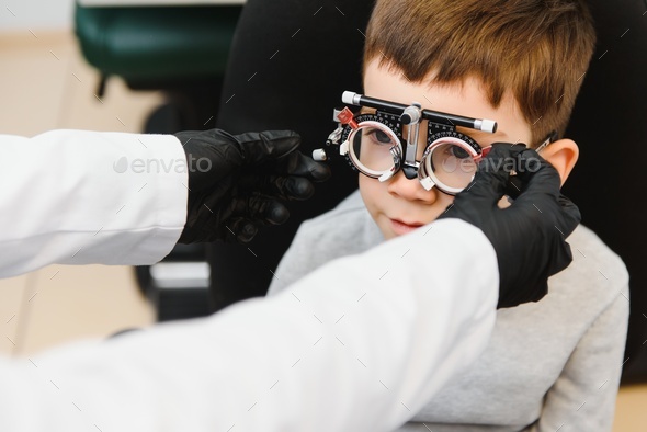Cheerful child boy in glasses checks eye vision pediatric ...
