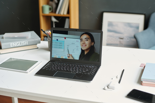 Laptop with English teacher on screen standing on desk with tablet ...
