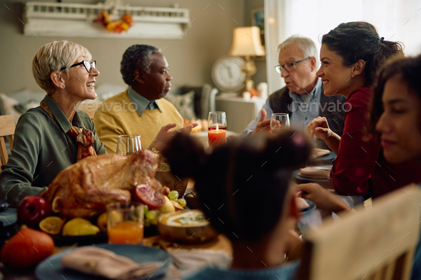 Happy multiracial extended family enjoying in conversation during ...