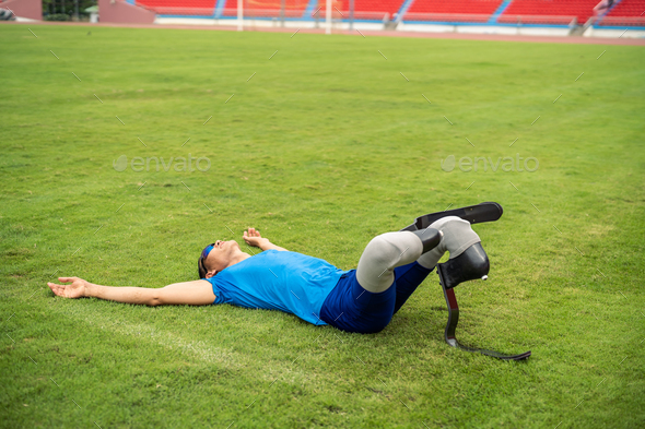 Asian para-athlete with prosthetic blades stretching leg in stadium ...