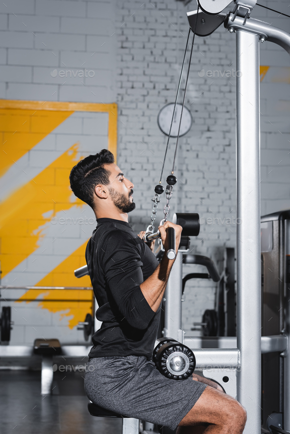 Side view of muslim sportsman training with lat pulldown machine in ...