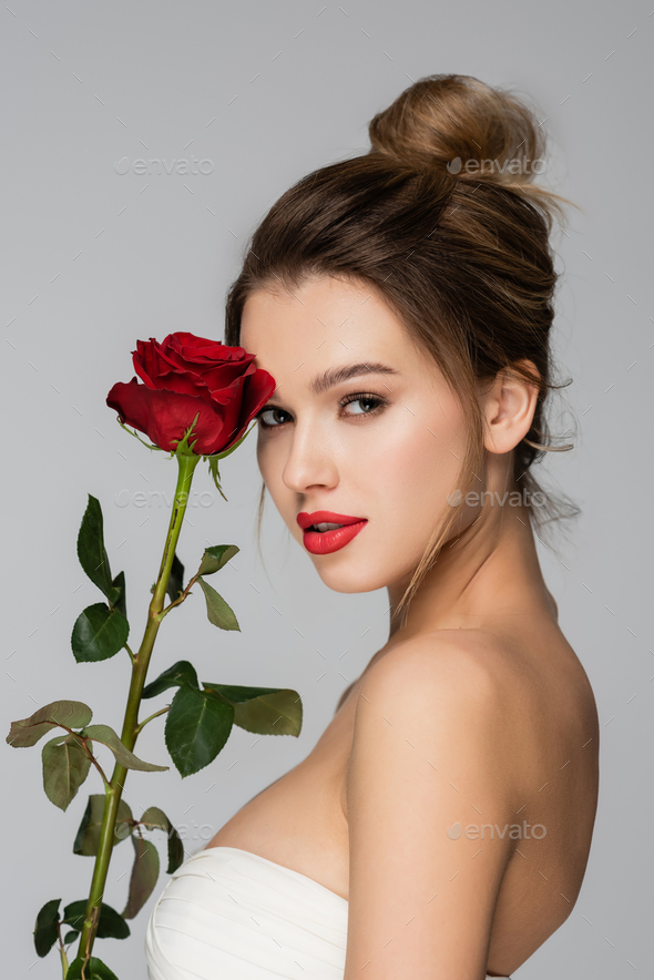 charming woman with perfect skin and red rose looking at camera ...